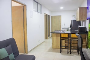 Um espaço compacto com cozinha compacta, sofá e pequena mesa de jantar.