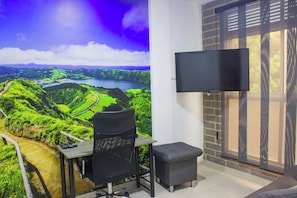 Quarto com escrivaninha, cadeira e televisão de tela plana na parede.