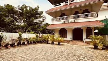 Um edifício com vários andares, um pátio, varandas e plantas em vasos.