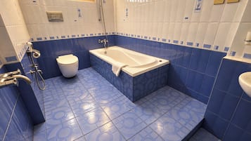Uma casa de banho com banheira, sanita e chuveiro.