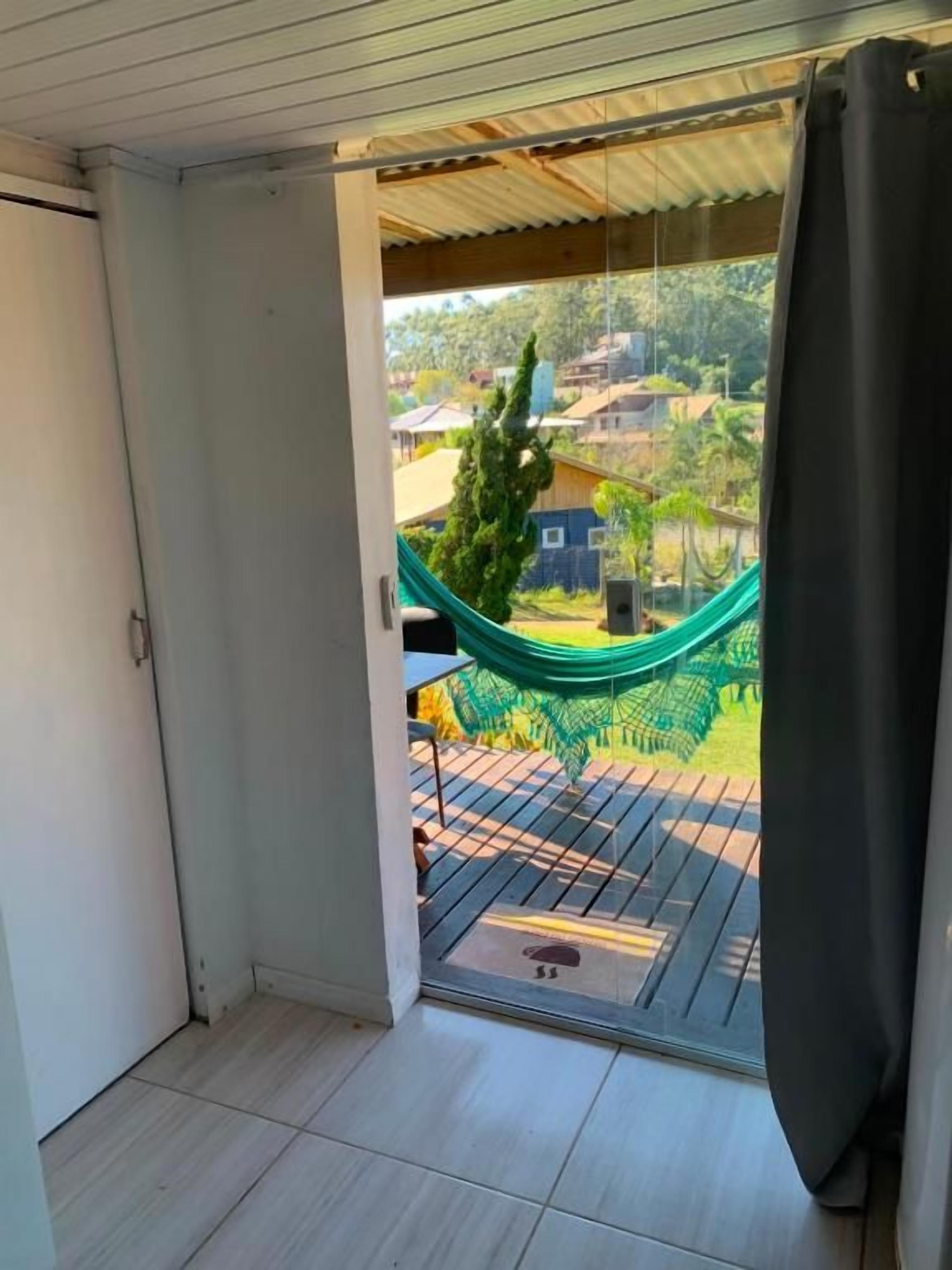 Varanda com vista para uma rede verde e um escorrega, piso de madeira e guarda-corpo de metal.