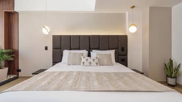 Quarto moderno com uma cama grande, cabeceira, abajures e um vaso com planta.