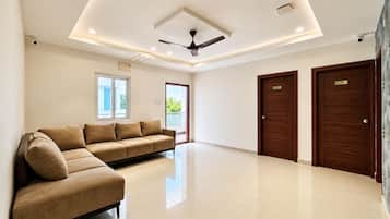 Quarto espaçoso com sofá, duas portas e ventilador de teto.