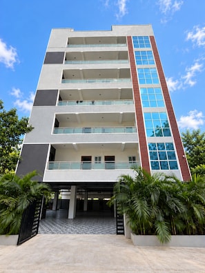 Um edifício de vários andares com design arquitetônico moderno, com varandas e grandes janelas.