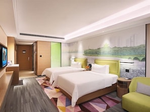 Quarto de hotel com duas camas, televisão, escrivaninha e parede com mural de paisagem urbana.