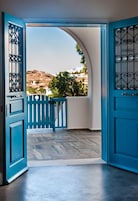 Abertura de porta que dá para uma varanda com vista para um morro e árvores.