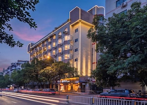 Hotel de vários andares com design moderno, com varandas e fachada bem iluminada.