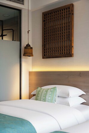 Quarto de hotel com uma cama, luminária pendente e cabeceira de madeira.