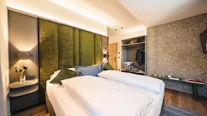 Quarto moderno com cama, mesas de cabeceira, guarda-roupa e um pequeno espaço de trabalho.