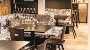 Espaço moderno com área de bar, assentos dispostos e divisória decorativa.
