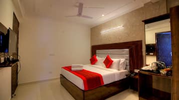 Quarto de hotel com cama, mesa de cabeceira, espelho, ventoinha no teto e televisão fixada na parede.