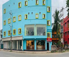 Edifício de vários andares com fachada azul e molduras de janelas amarelas, apresentando um restaurante no térreo com mesas visíveis e uma placa com a inscrição 'KNIGHT GUEST HOUSE'.