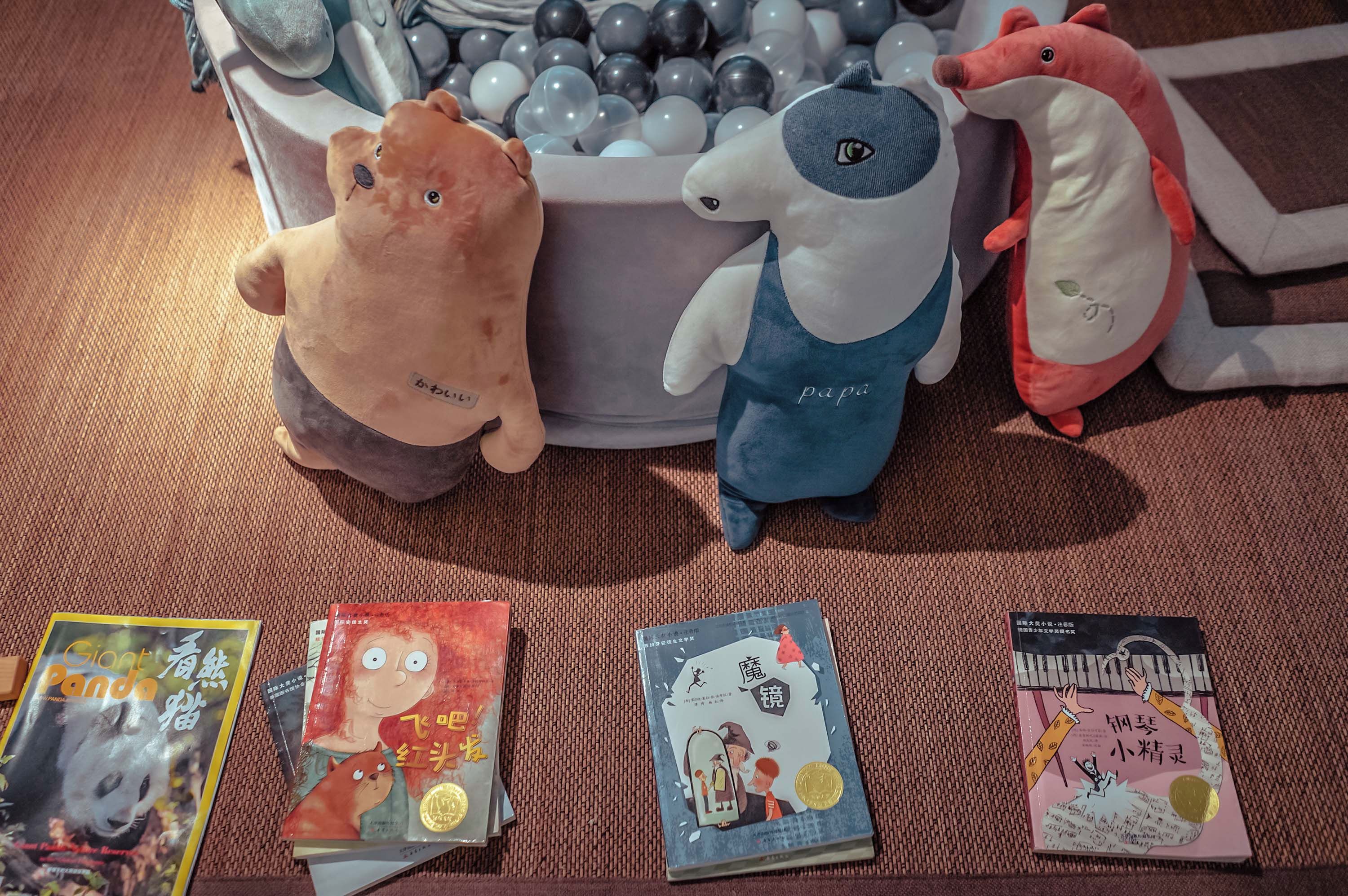 Uma seleção de brinquedos de pelúcia e livros sobre uma superfície texturizada.