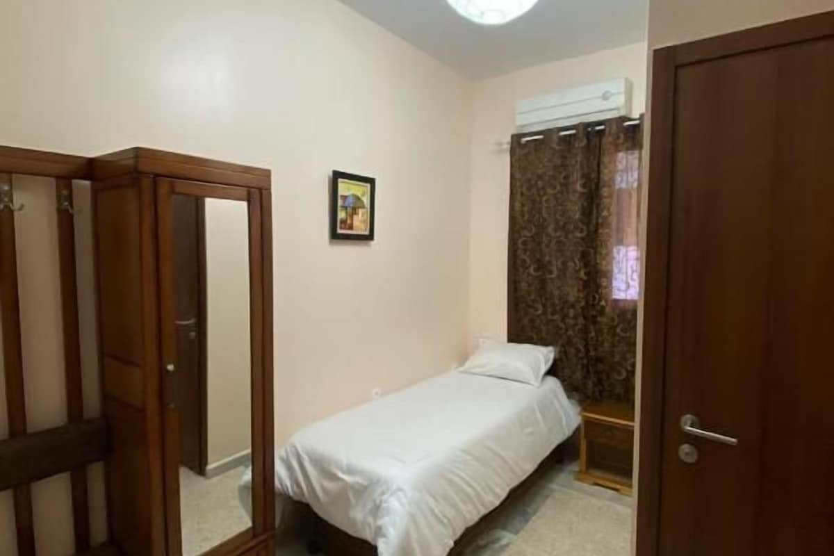 Quarto com uma cama de solteiro, um guarda-roupa e uma porta.