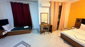 Quarto de hotel com cama, escrivaninha e cadeira, espelho e janela com cortinas.