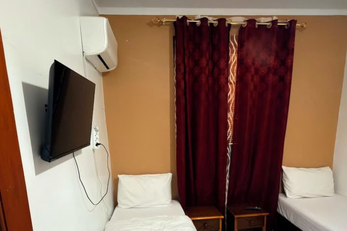 Quarto com cama, televisão na parede e janela com cortinas.