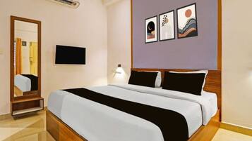 Quarto de hotel com cama, espelho, televisão de tela plana e obras de arte na parede.