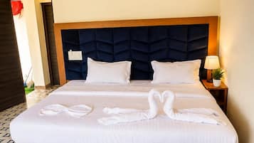 Quarto de hotel com cama, cabeceira, mesa de cabeceira, luminária e ventilador de teto.