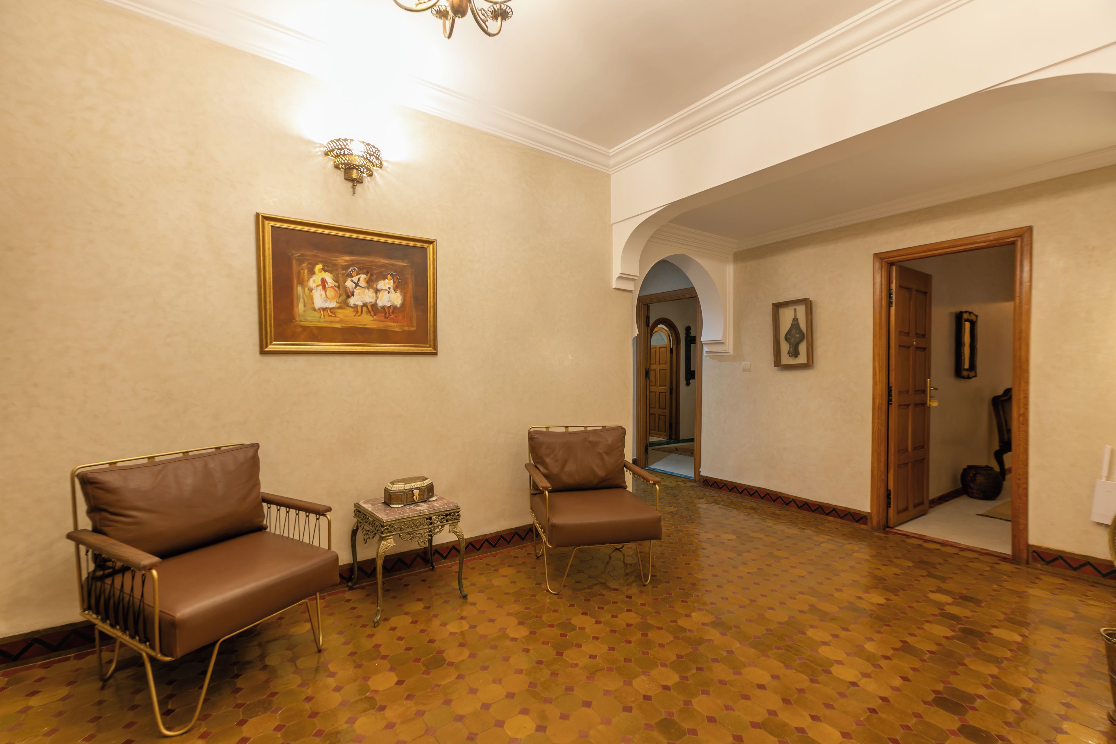 Quarto com duas poltronas de couro, uma mesinha e um quadro na parede.