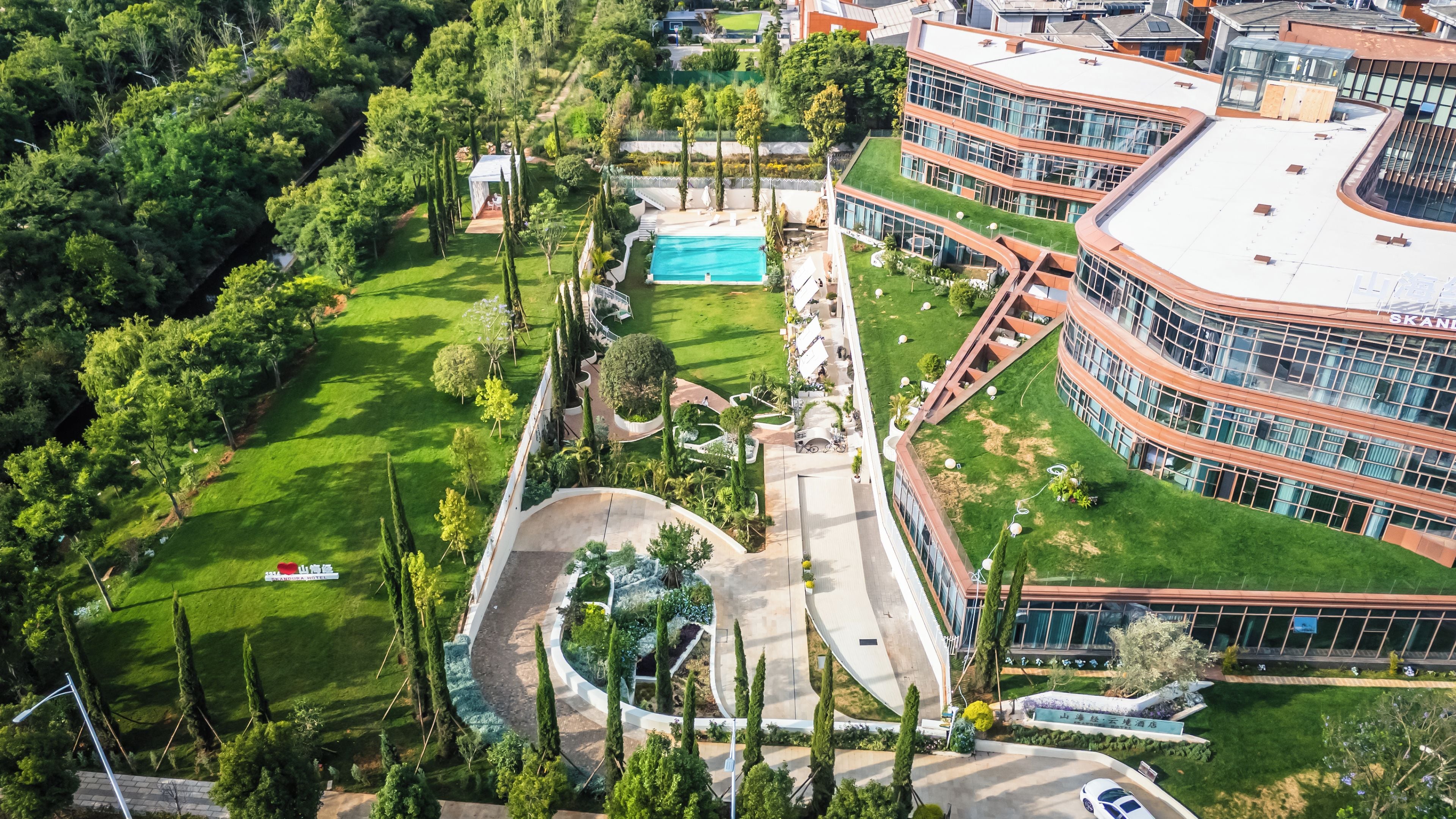 Vista aérea de um hotel com piscina, jardins bem cuidados e arquitetura moderna.