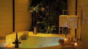 Uma área de spa com hidromassagem, velas e uma estatueta de coelho decorativa.