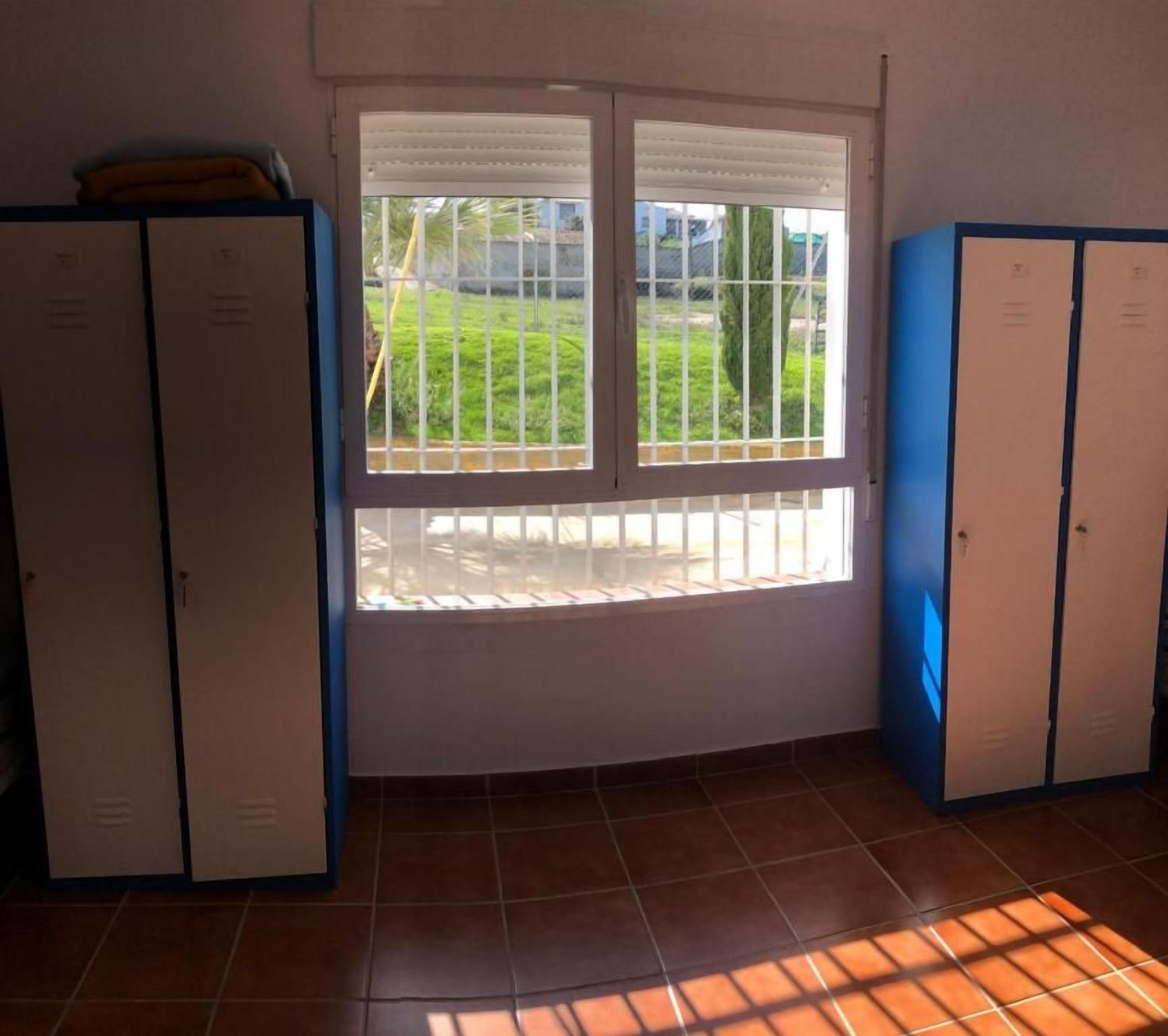 Quarto com janela, dois armários e piso ladrilhado.