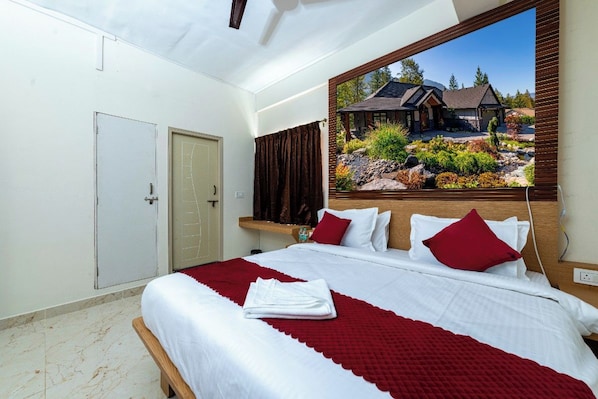 Quarto de hotel com uma cama grande, vista de uma casa pela janela e uma porta.