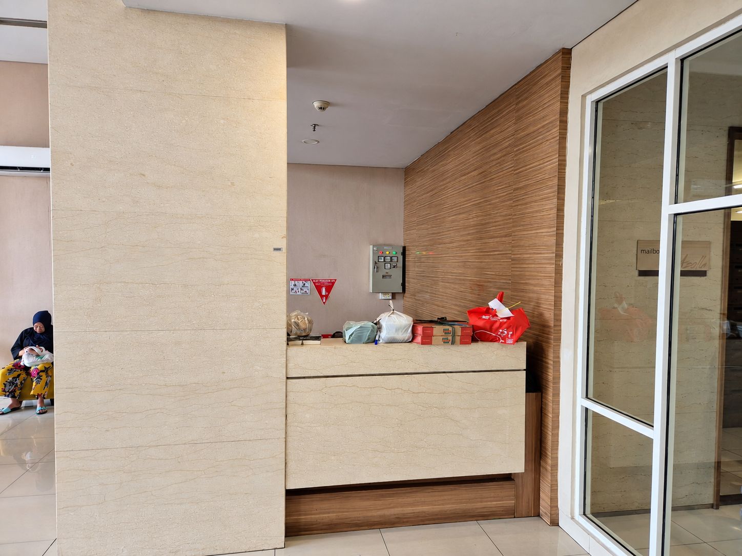 Uma mesa de recepção com painel de madeira, um detector de incêndio e uma caixa de correio.