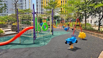 Uma área de recreação com escorrega, balanços e estrutura de escalada.