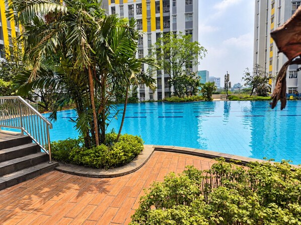 Piscina rodeada por vegetação e edifícios modernos.