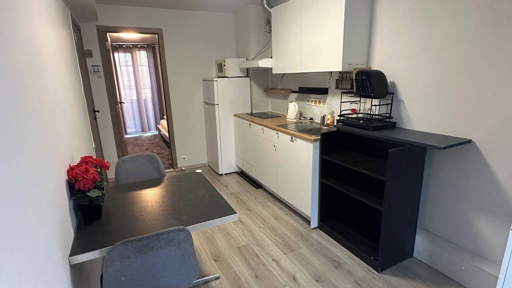 Cozinha compacta com área de refeições, geladeira, pia e armário preto.