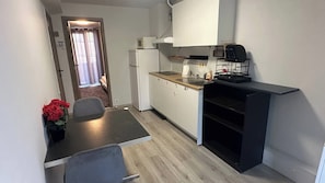 Cozinha compacta com área de refeições, geladeira, pia e armário preto.