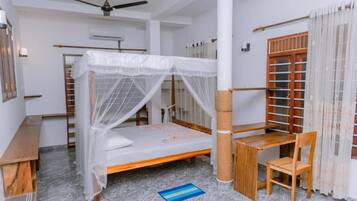 Quarto com cama, escrivaninha, cadeira, ventoinha no teto e janela com cortinas.