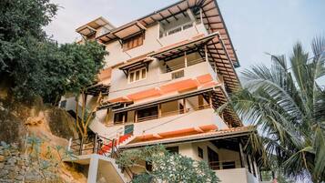 Um edifício com várias andares, varandas e uma escadaria que leva à entrada.