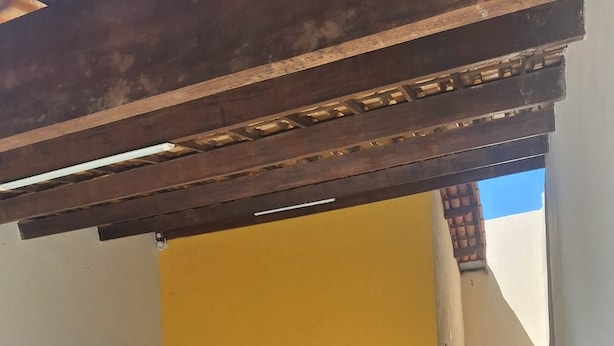Pátio aberto com parede amarela e chão de azulejos.