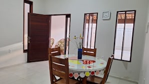 Uma sala de jantar com uma mesa redonda, cadeiras, um relógio e uma porta.