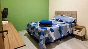 Quarto com cama, mesa de cabeceira e uma cadeira.