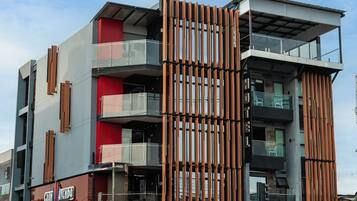 Um edifício moderno de vários andares, com uma combinação de varandas e grandes janelas.