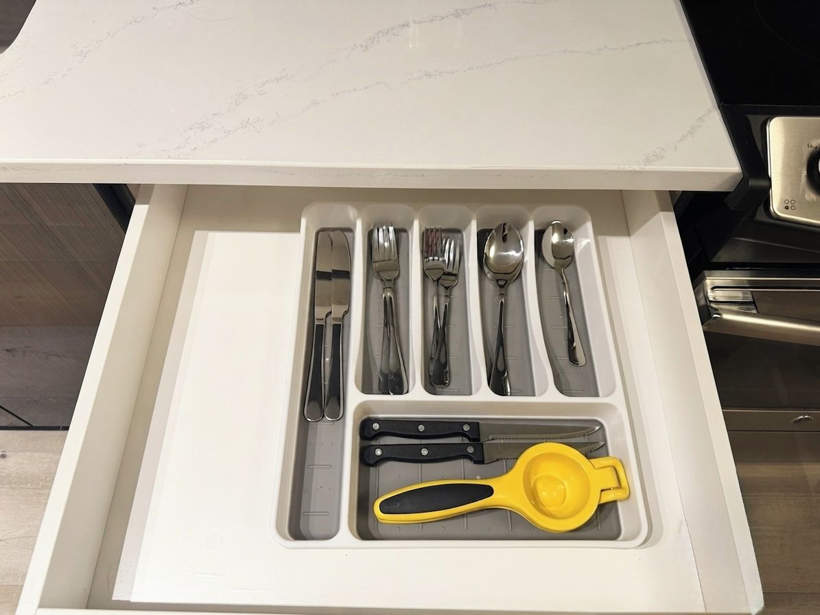 Uma gaveta com utensílios e um espremedor de frutas cítricas amarelas.