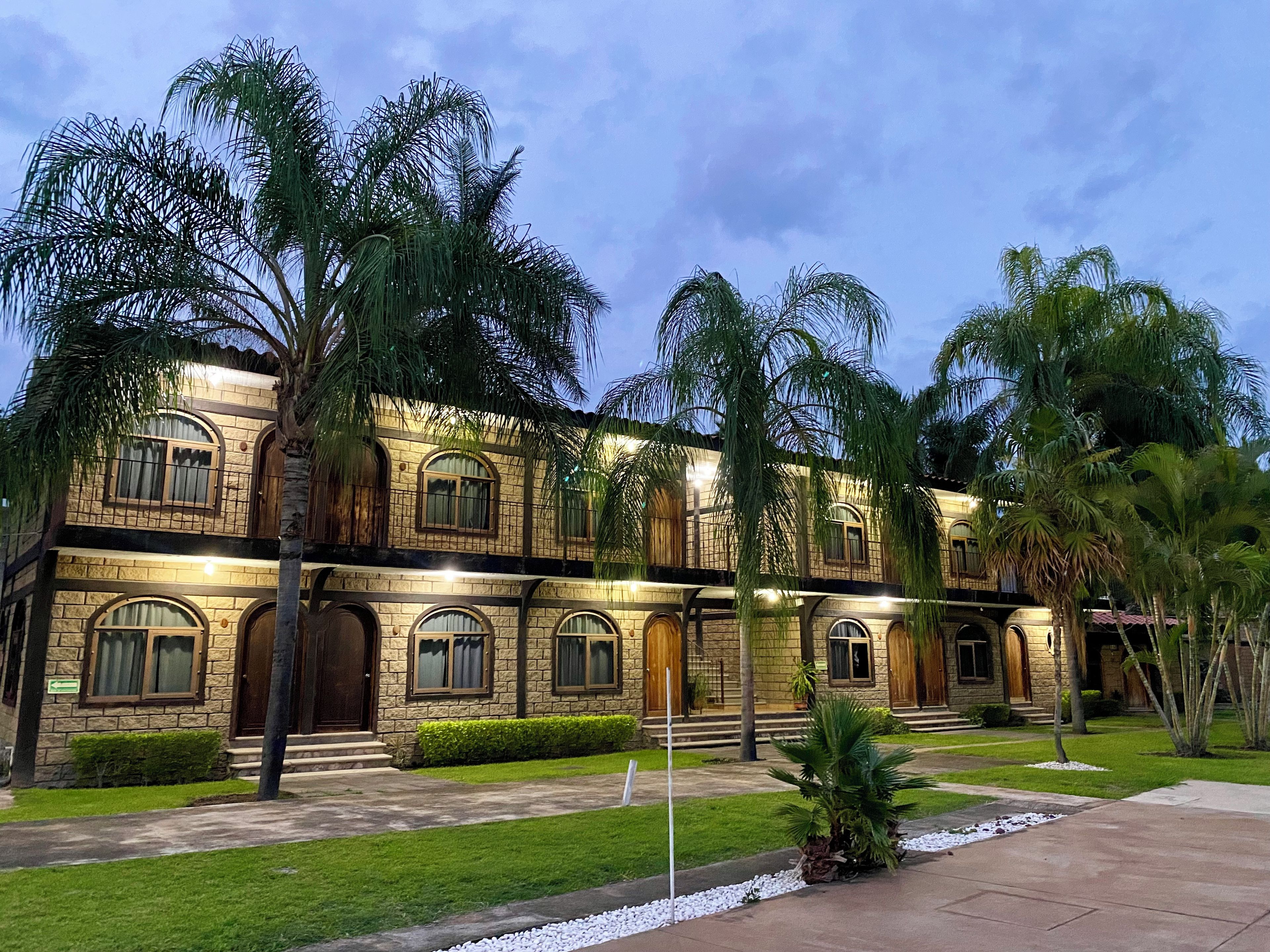 Um edifício de vários andares com fachada de pedra, janelas em arco e um gramado bem cuidado.
