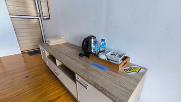 Uma cozinha compacta com bancada de madeira, chaleira, garrafas de água, cafeteira e aviso indicando disponibilidade de Wi-Fi.