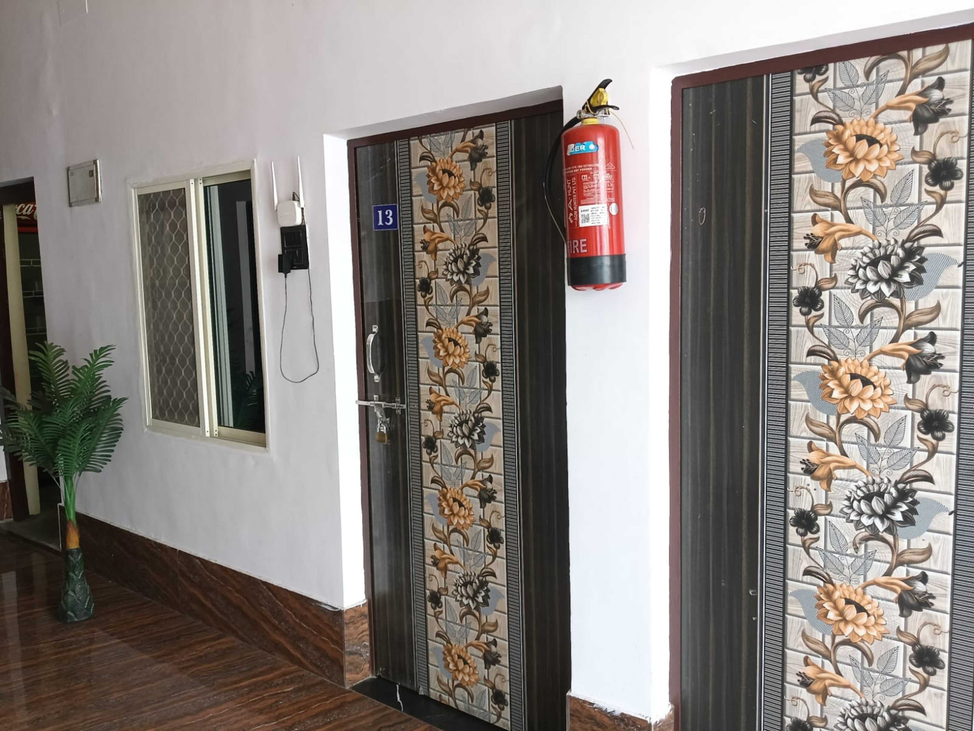 Corredor com portas, um extintor e um vaso de planta.