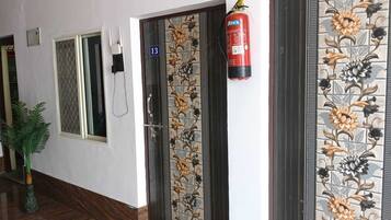 Corredor com portas, um extintor e um vaso de planta.