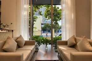 Uma sala de estar moderna com dois sofás, uma mesa de centro e vista para o horizonte urbano através de grandes janelas.