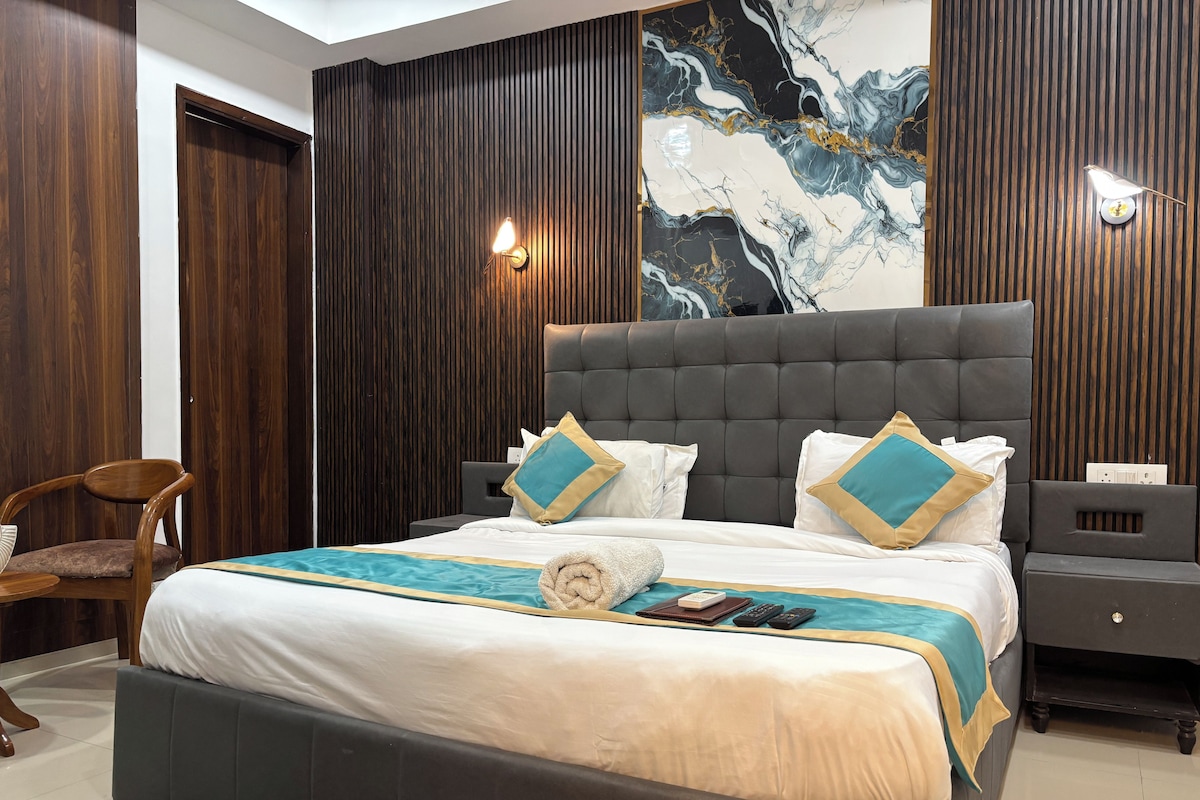 Quarto moderno com uma cama grande, guarda-roupa de madeira, área de estar e parede de mármore.