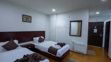 Quarto de hotel com duas camas, mesa de cabeceira, espelho, porta e radiador.