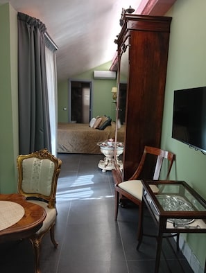 Quarto de hotel com cama, televisão, escrivaninha e cadeira, espelho e janela com cortinas.