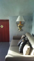 Quarto com sofá, luminária na parede e parede vermelha.