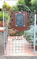 Um portão de ferro forjado com uma placa decorativa retratando o perfil de uma mulher.