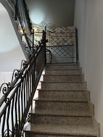 Uma escadaria com corrimão de metal e um portão decorativo no topo.